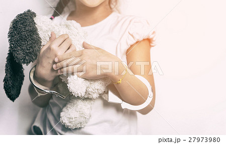 Child holding a doll with her hand in handcuffedの写真素材 [27973980] - PIXTA