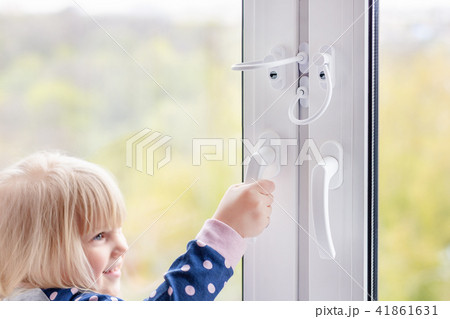 Little cute toddler girl trying to open window...の写真素材 [41861631] - PIXTA