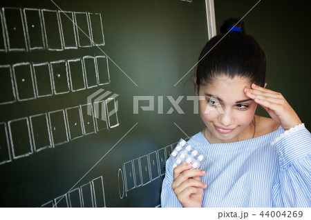 Upset student with piils stays near blackboard の写真素材 [44004269] - PIXTA