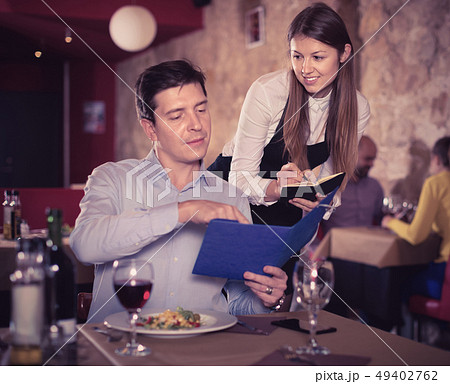 Hospitable waitress helping handsome man with...の写真素材 [49402762] - PIXTA