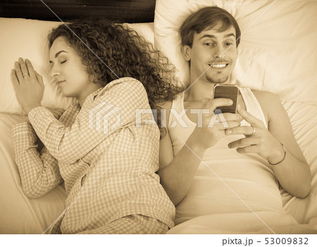Man texting to lover as wife sleeping .の写真素材 [53009832] - PIXTA