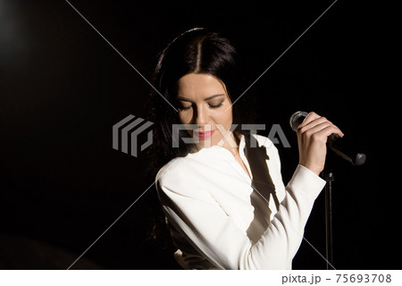 Portret of a singer with mic in hand singing popular song on stage in ...