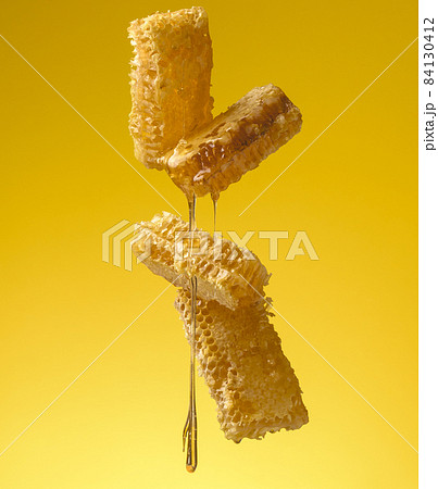 flowing honey over honeycomb on yellow backgroundの写真素材 [84130412] - PIXTA