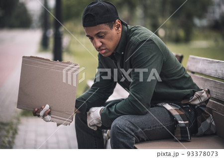 Unhappy man holding cardboard sitting on benchの写真素材 [93378073] - PIXTA