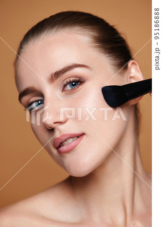 woman applying blush on cheeks with make up brush 95186888 PIXTA