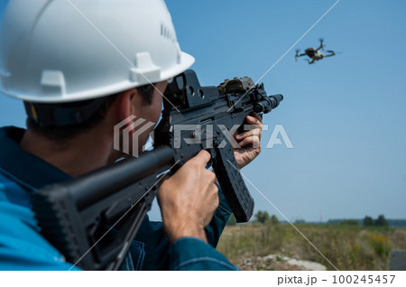 Caucasian man in a helmet shoots a flying drone with a rifle ...