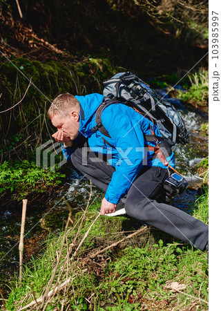Hiker drinking stream water in mountain. Adult...の写真素材 [103985997] - PIXTA