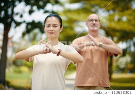 Smiling man and woman doing fist palm salute when practicing tai chi ...