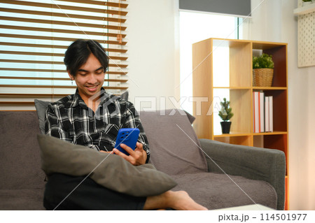 Cheerful young Asian man checking news feed or...の写真素材 [114501977] - PIXTA
