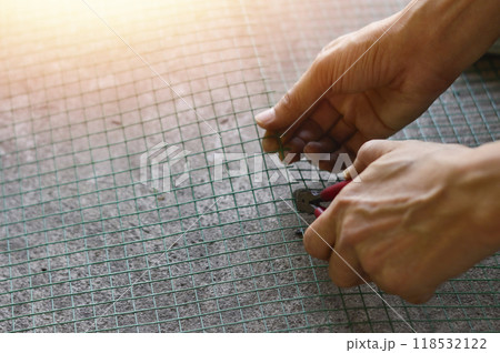 Technician uses pliers to cut green wire meshの写真素材 [118532122] - PIXTA
