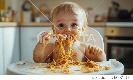 A baby delightfully eating spaghetti, making a...のイラスト素材 [126007198 ...