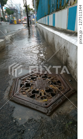 Hexagonal manhole cover sits on wet street with...のイラスト素材 [127511344 ...