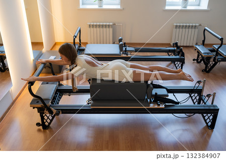 Woman doing Swan exercise on Pilates Reformer...の写真素材 [132384907] - PIXTA